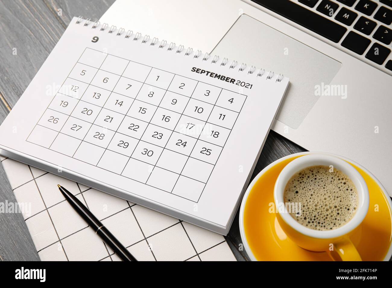 Flip paper calendar with laptop, cup of coffee and stationery on table ...