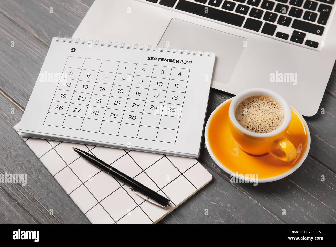 Flip paper calendar with laptop, cup of coffee and stationery on table ...