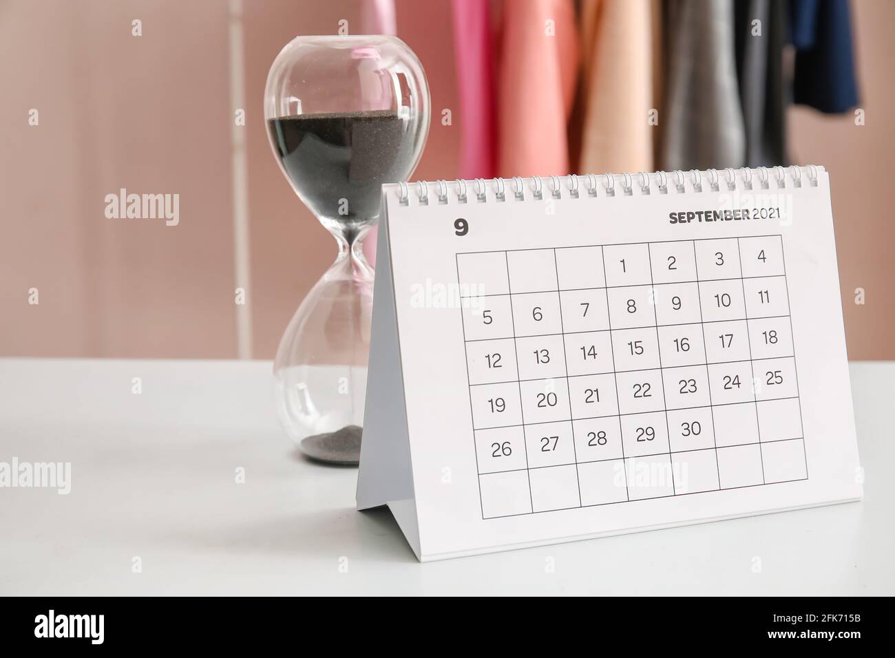 Flip paper calendar with hourglass on table in office Stock Photo - Alamy