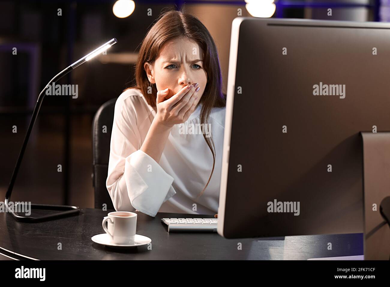Sleepy young woman using computer late at night. Addiction concept ...