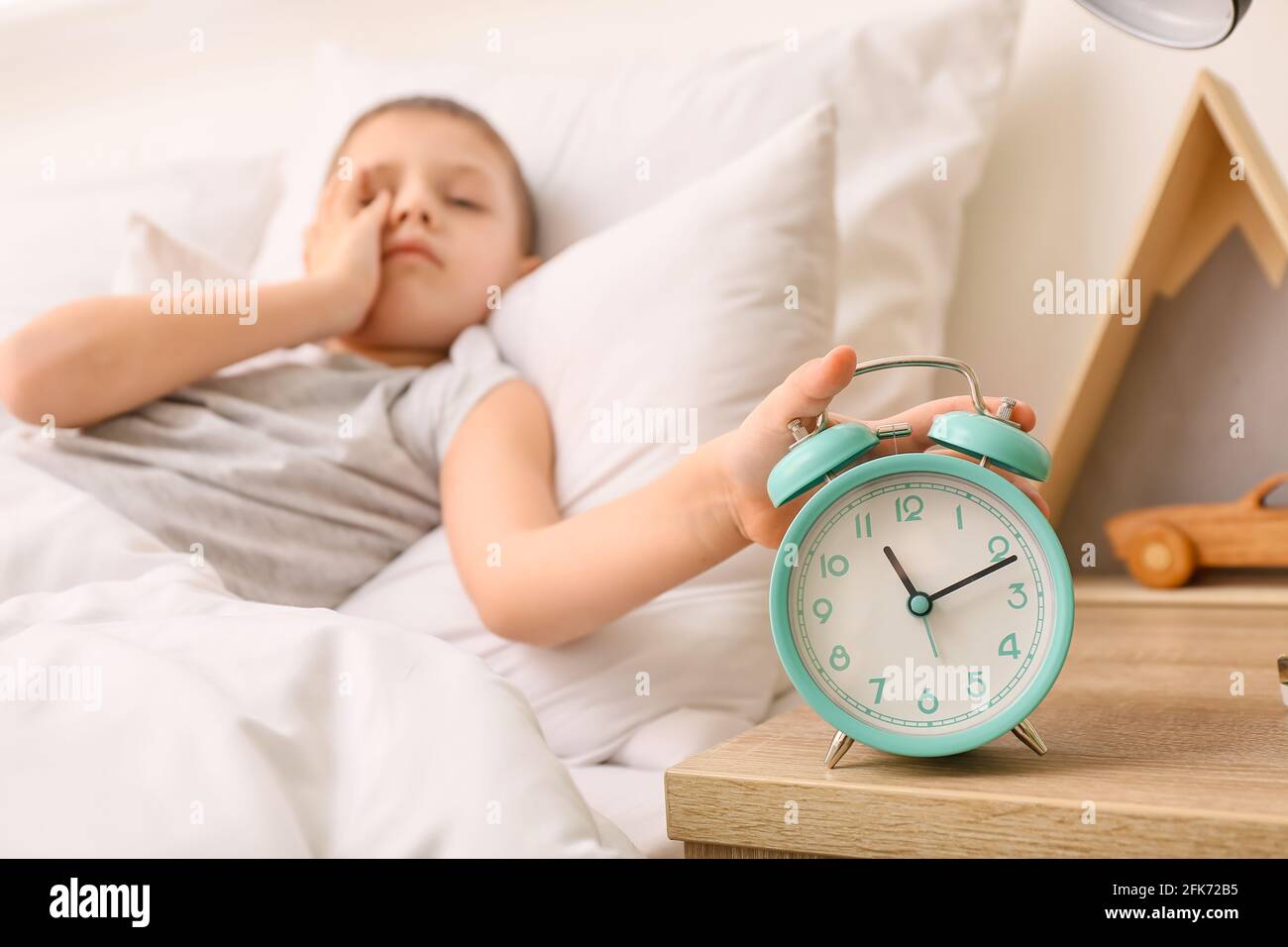 Morning of sleepy little boy turning off alarm clock Stock Photo - Alamy