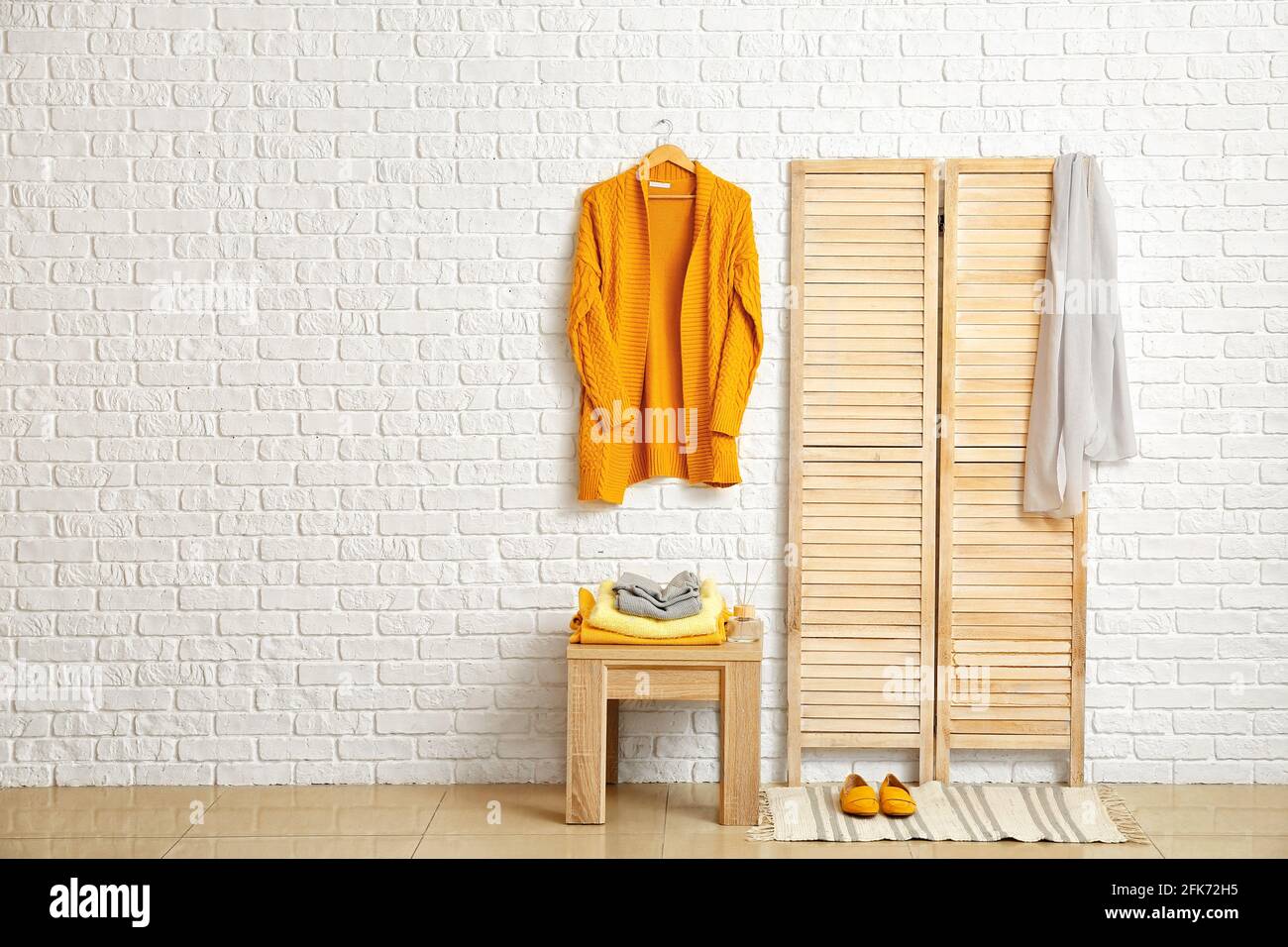 Folding screen and table with stylish clothes in modern room Stock ...