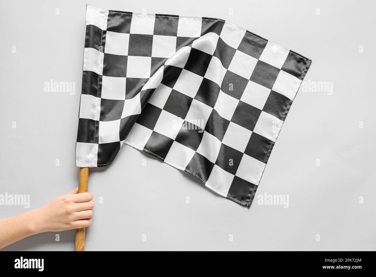 Hand with racing flag on light background Stock Photo - Alamy
