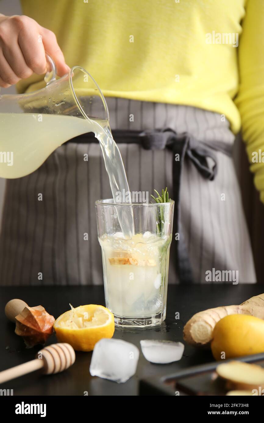 Woman pouring ginger lemonade from jug into glass in kitchen Stock ...