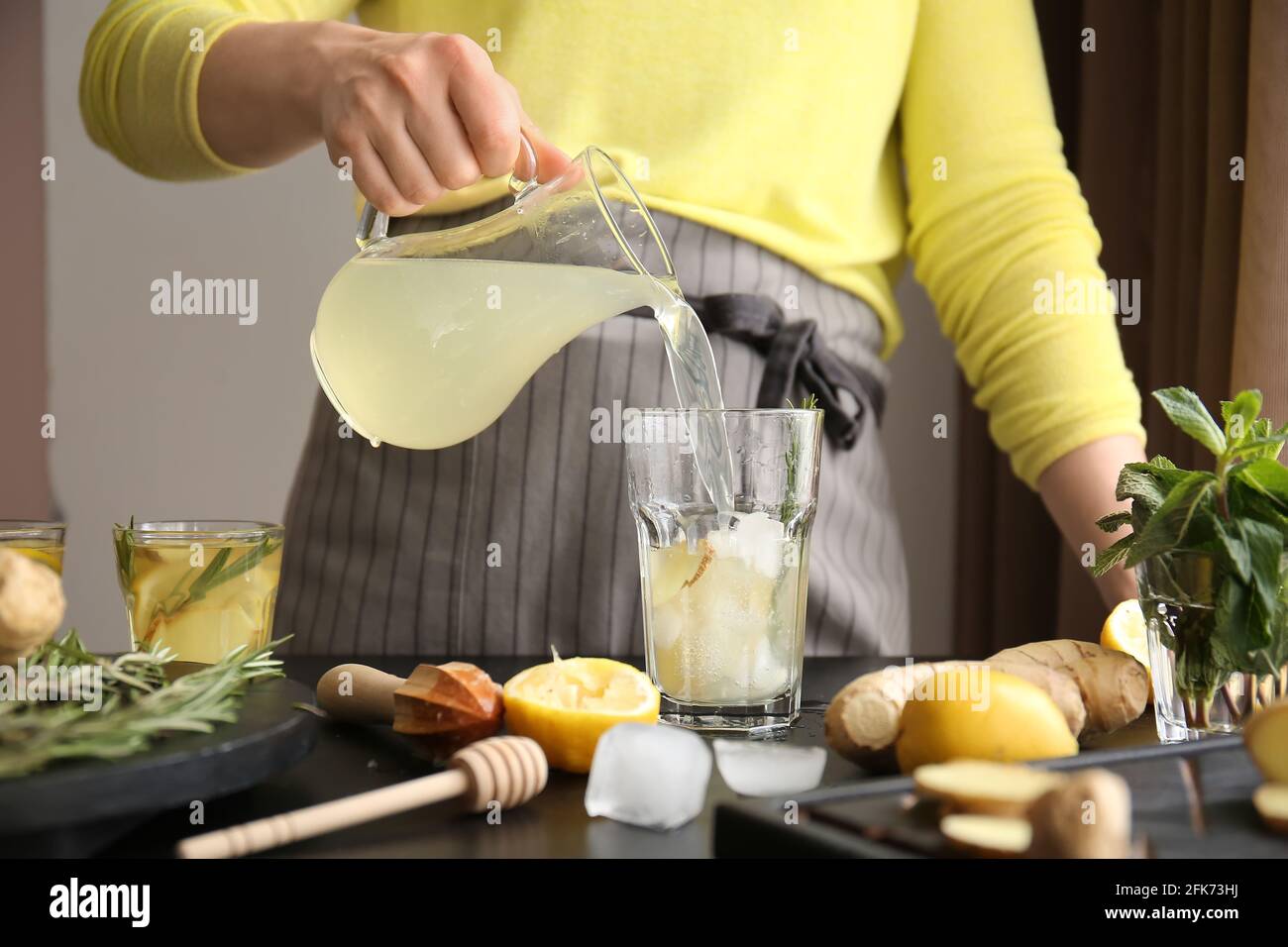 Woman pouring ginger lemonade from jug into glass in kitchen Stock ...