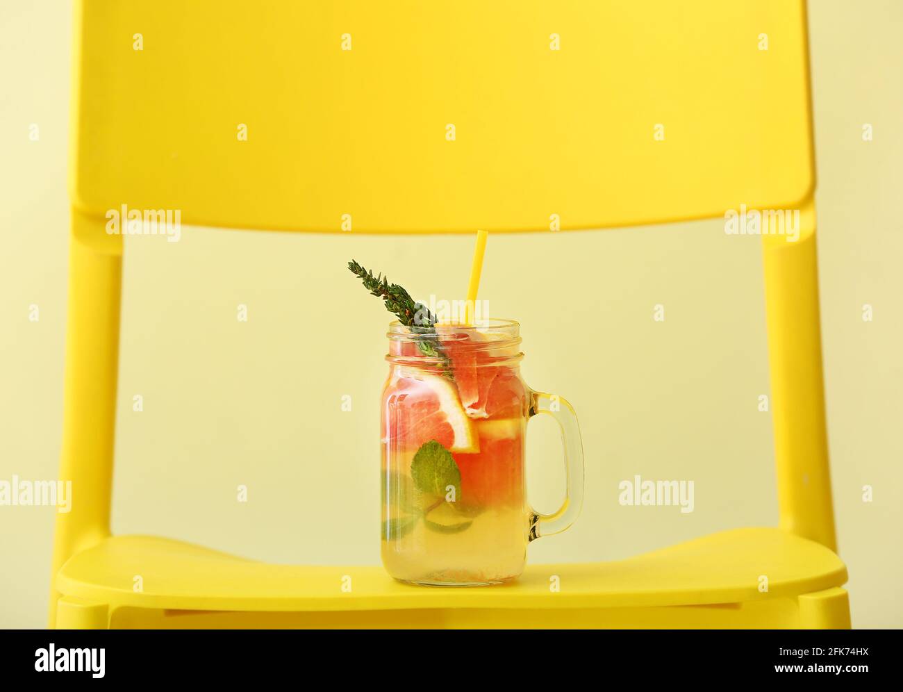 Mason jar of tasty grapefruit lemonade on chair against color ...