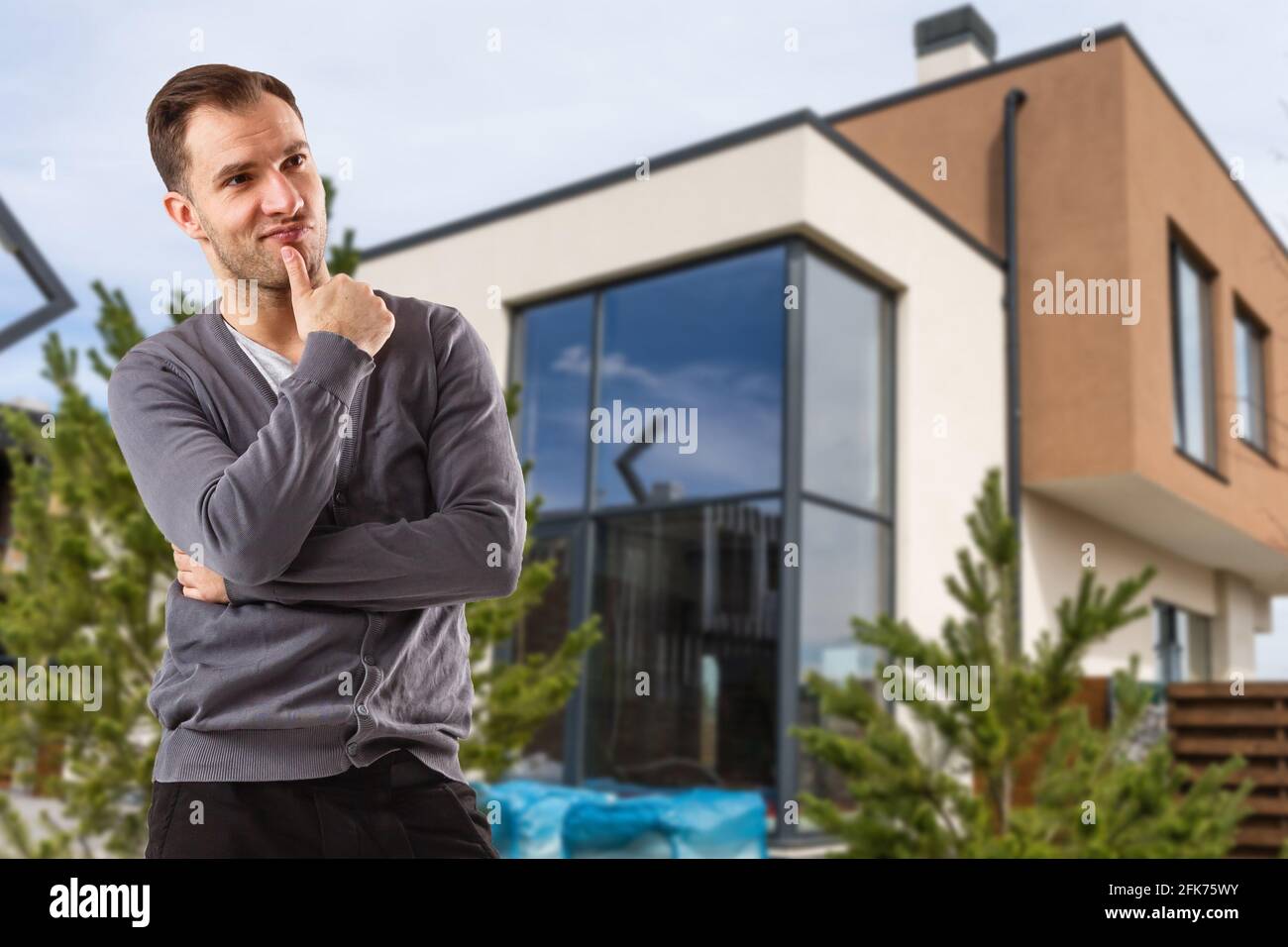 Cheerful man standing in front of new house Stock Photo - Alamy