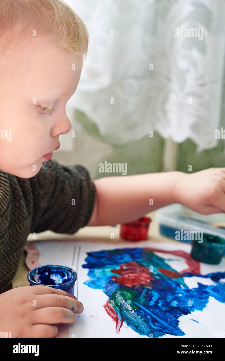 A three-year-old boy paints with gouache coloring, leisure and child ...