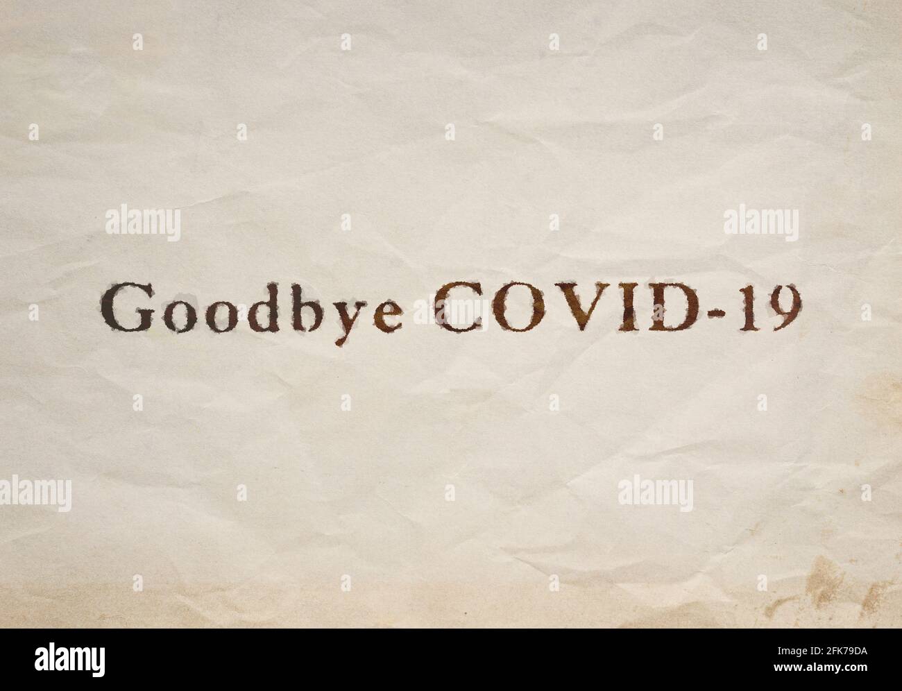 Close-up of "Goodbye COVID-19" text on an old, stained and crumpled ...