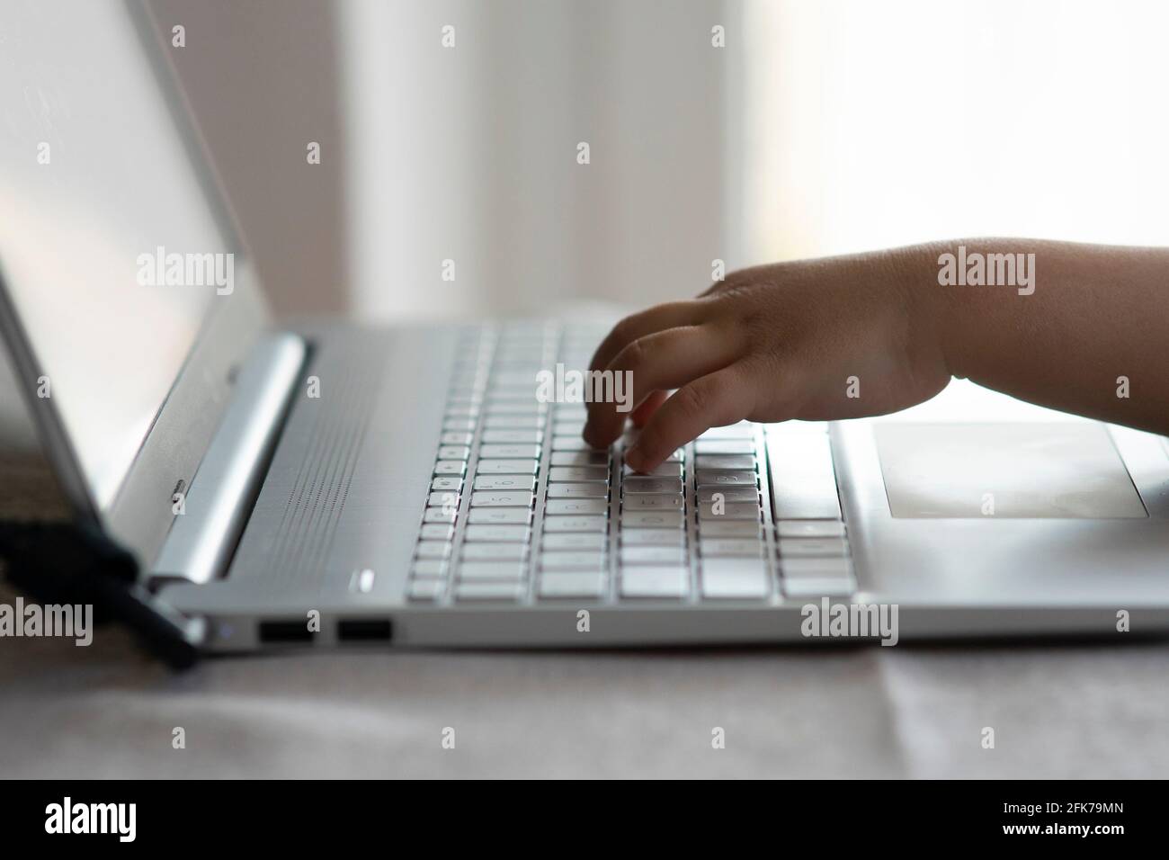 Hand of little girl using a notebook keyboard. Concept of distance ...