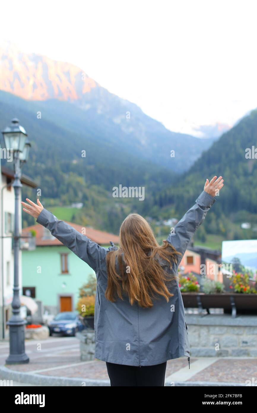 Back view of woman standing with raised hands in mountain village Stock ...