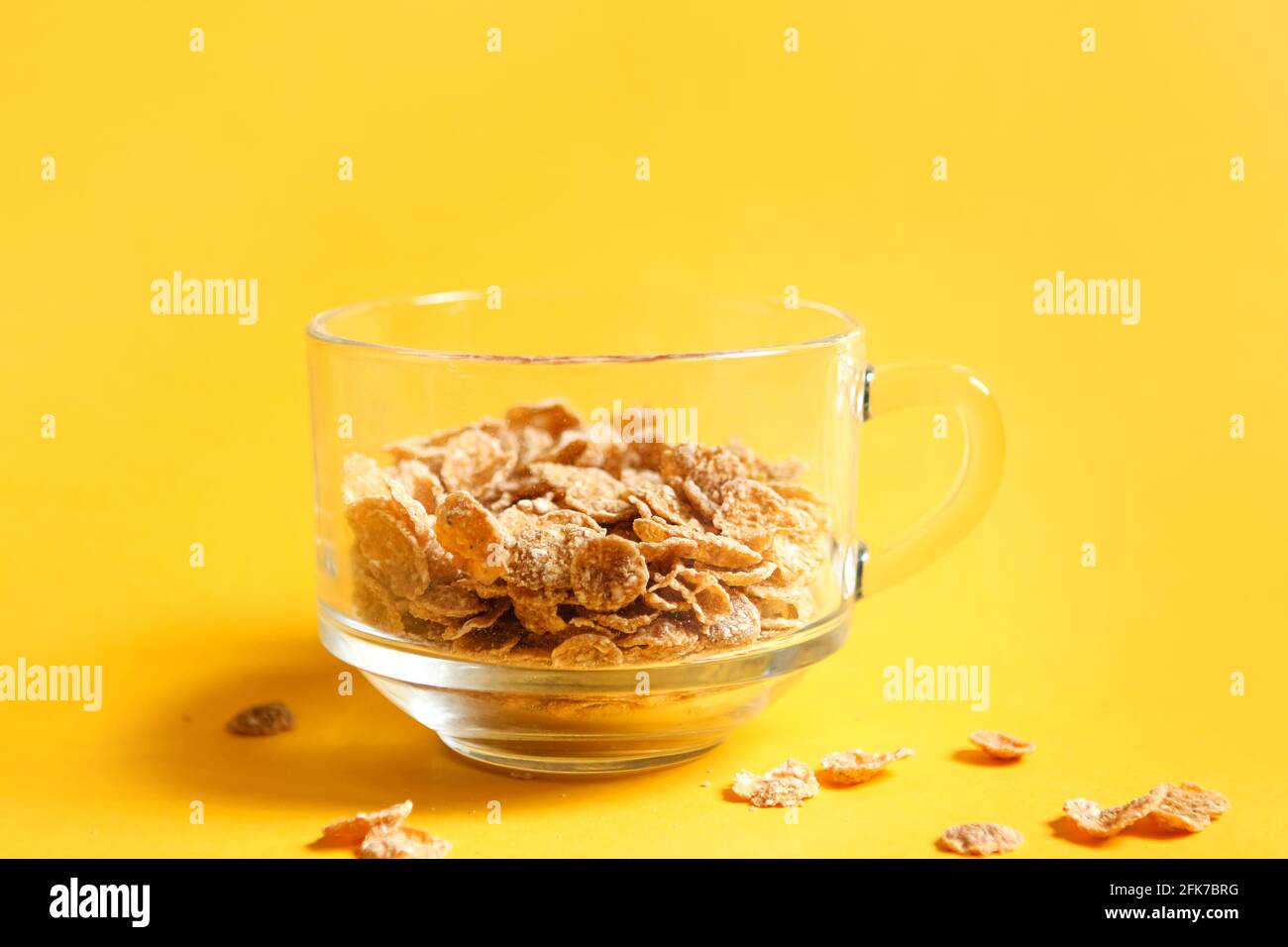 Transparent bowl with corn and multigrain flakes on a yellow background ...