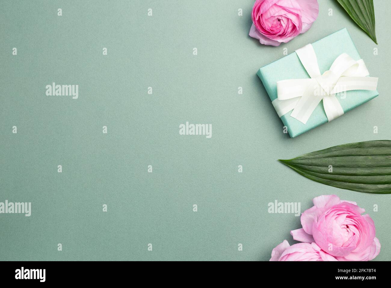 Gift boxes with flower and leaf on green background. flat lay, top view ...