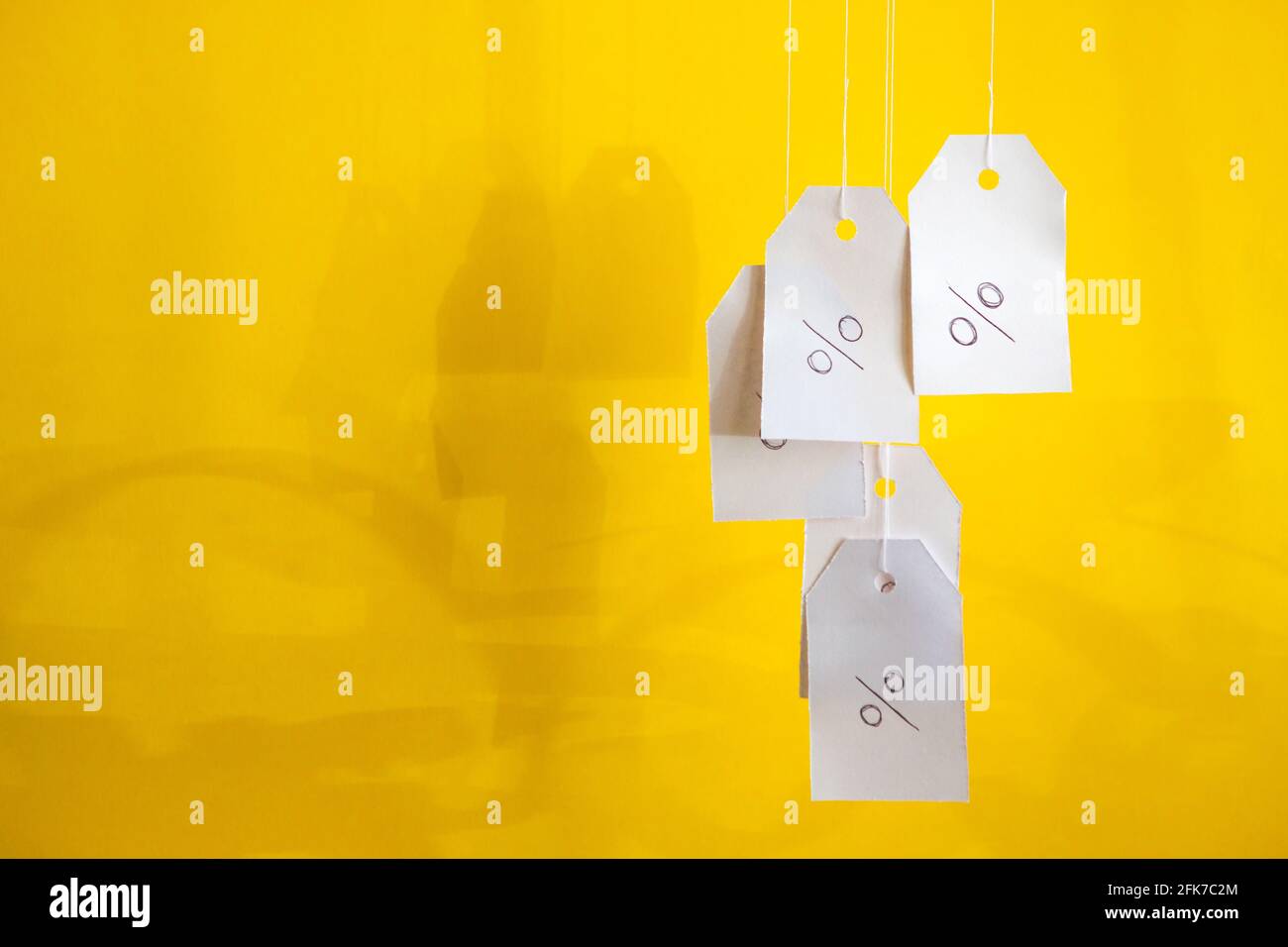 White tags with the percent sign hang on strings on a yellow background ...