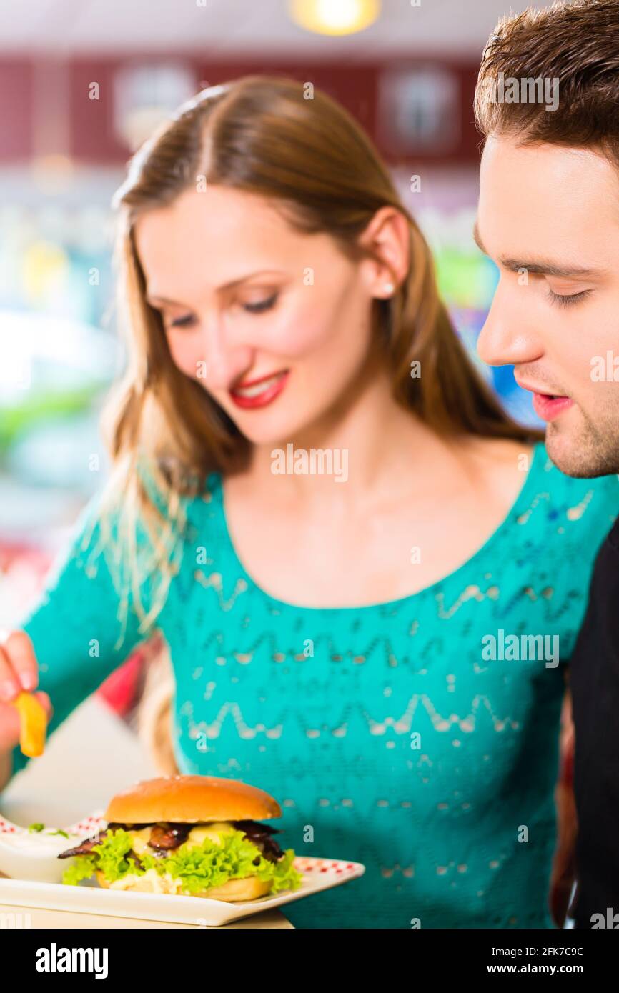 Friends or couple eating fast food with burger and fries in American ...
