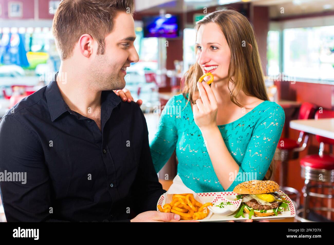 Friends or couple eating fast food with burger and fries in American ...