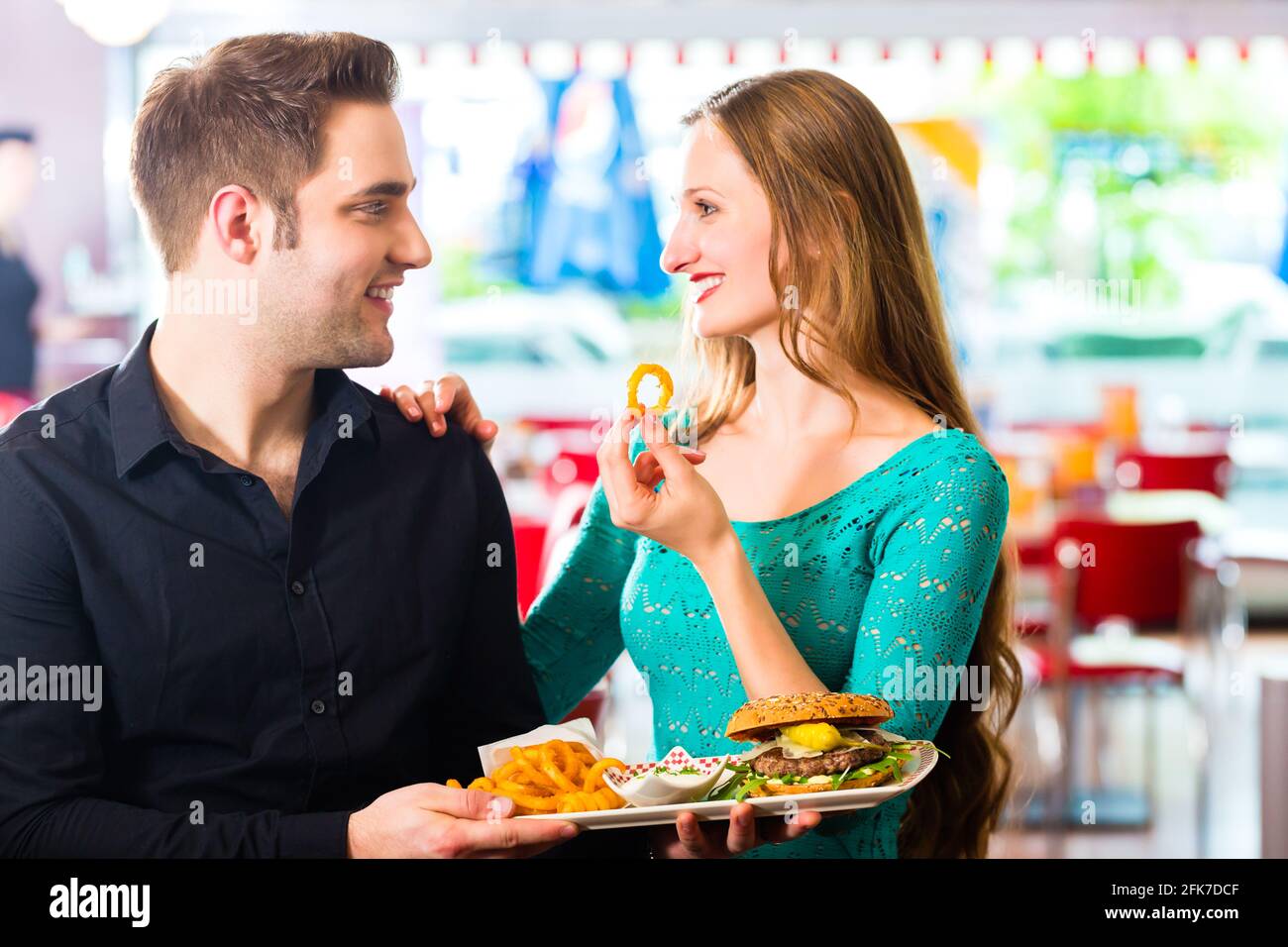 Friends or couple eating fast food with burger and fries in American ...