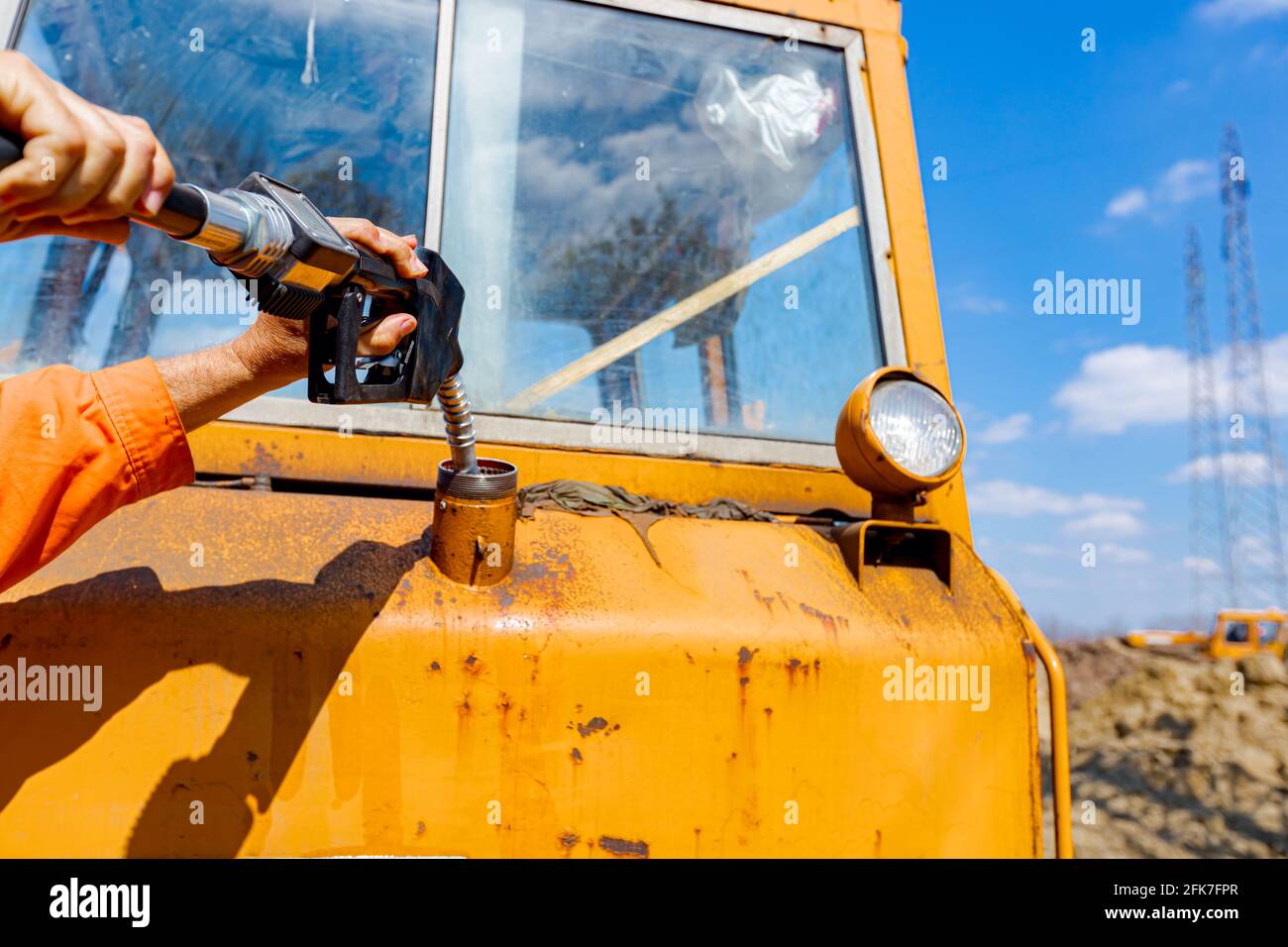 Worker holding fuel pump gun inserted in the reservoir of construction ...