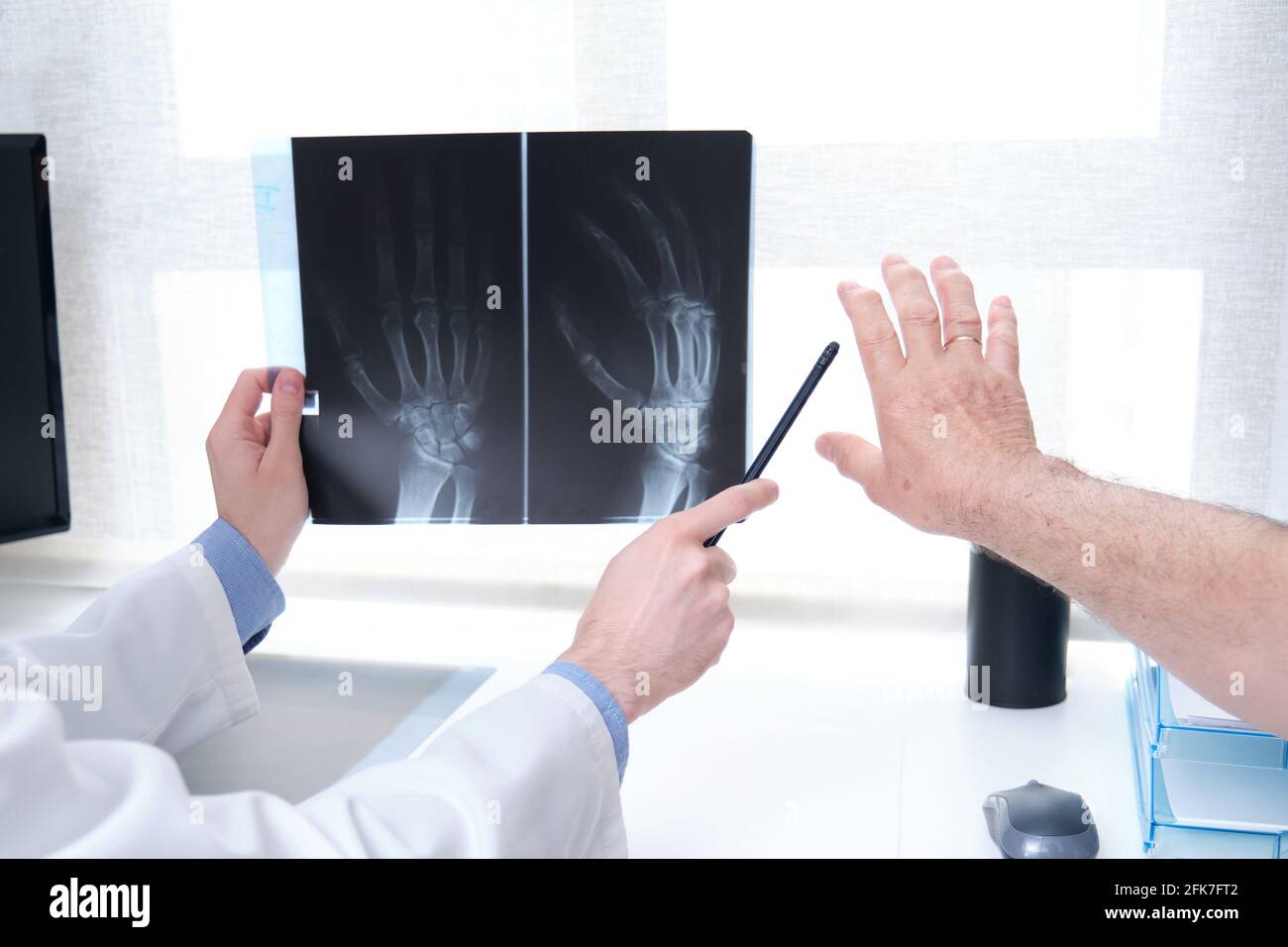 Young doctor examining x-ray of hands of a senior patient with ...