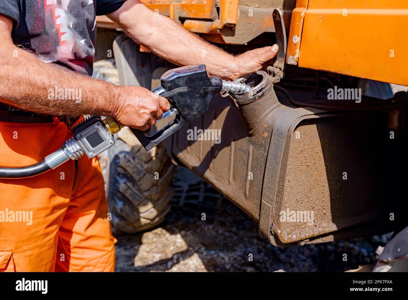 Worker holding fuel pump gun inserted in the reservoir of construction ...