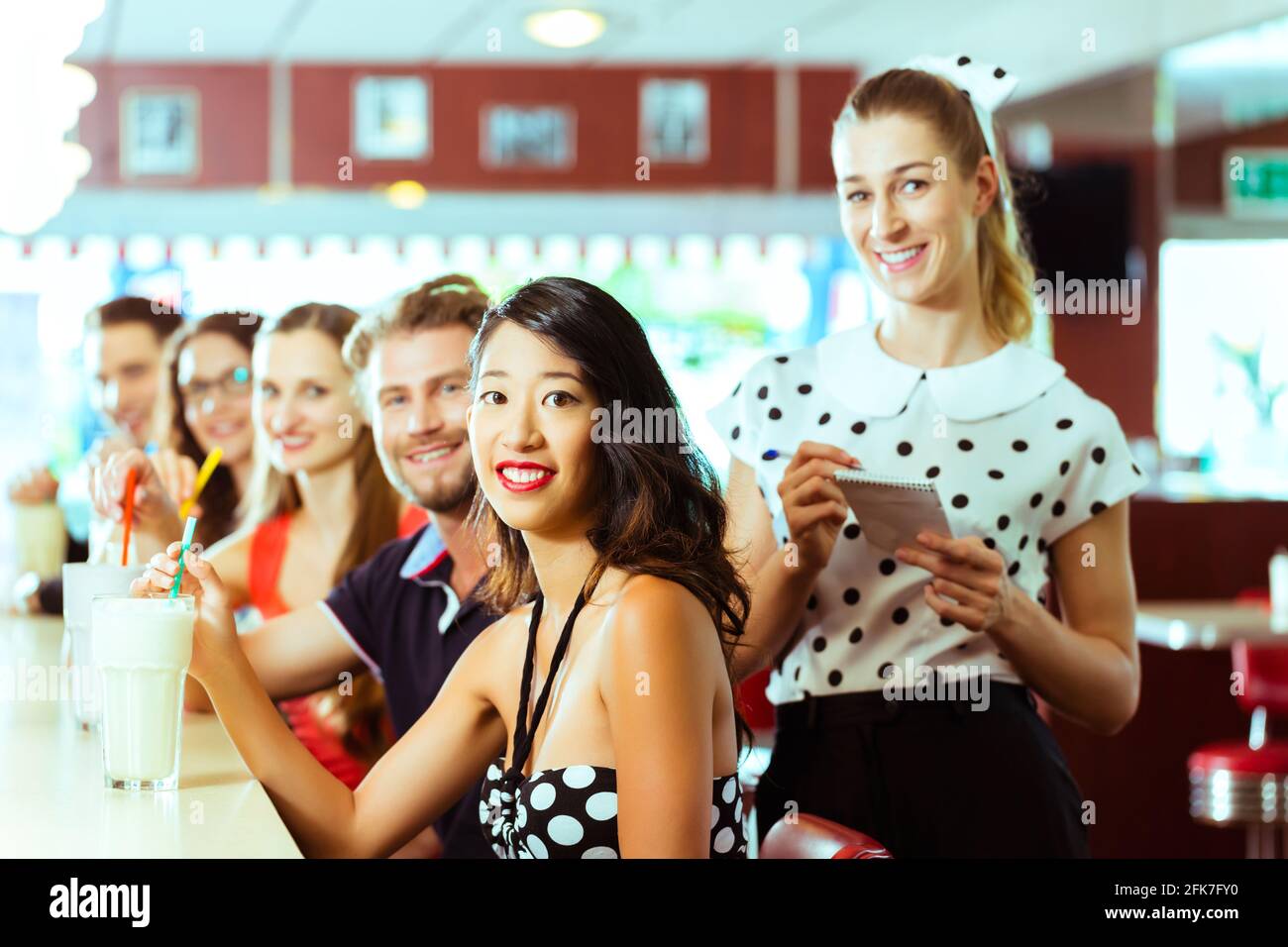 Friends or couples eating fast food and drinking milk shakes on bar in ...