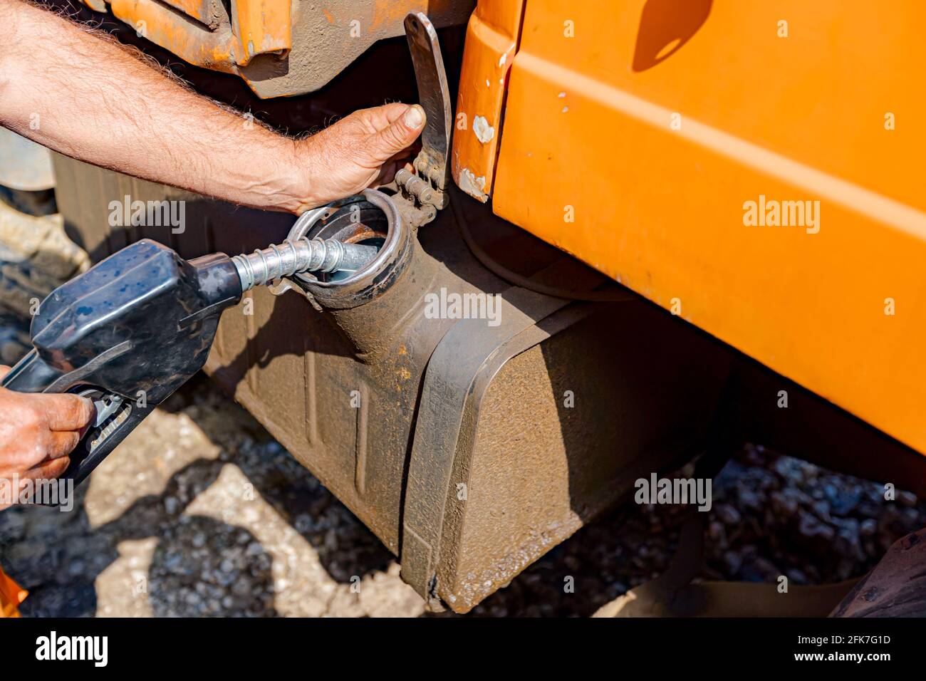 Worker holding fuel pump gun inserted in the reservoir of construction ...