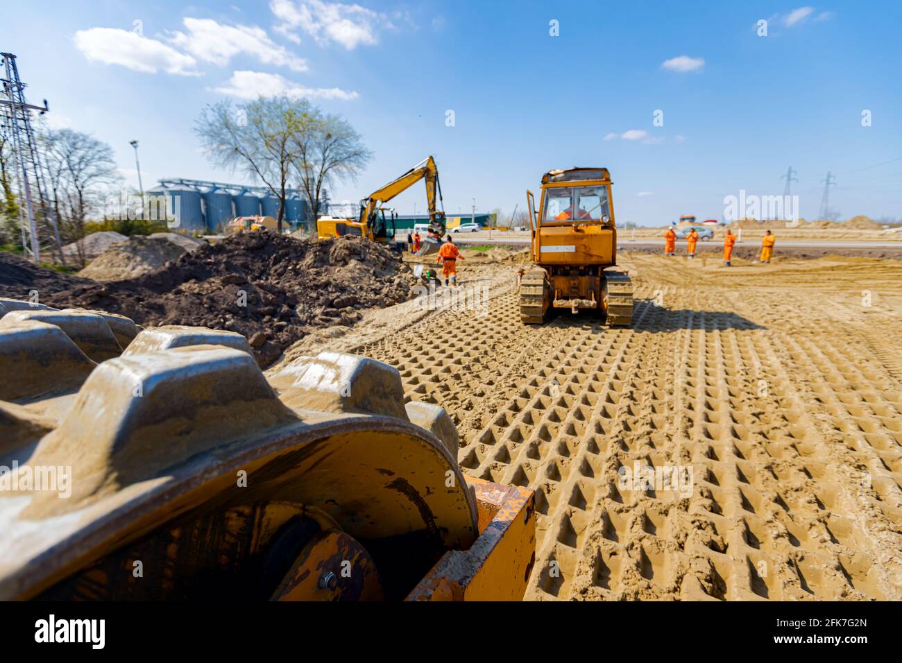 View over roller with spikes on bulldozer, excavator and truck with ...
