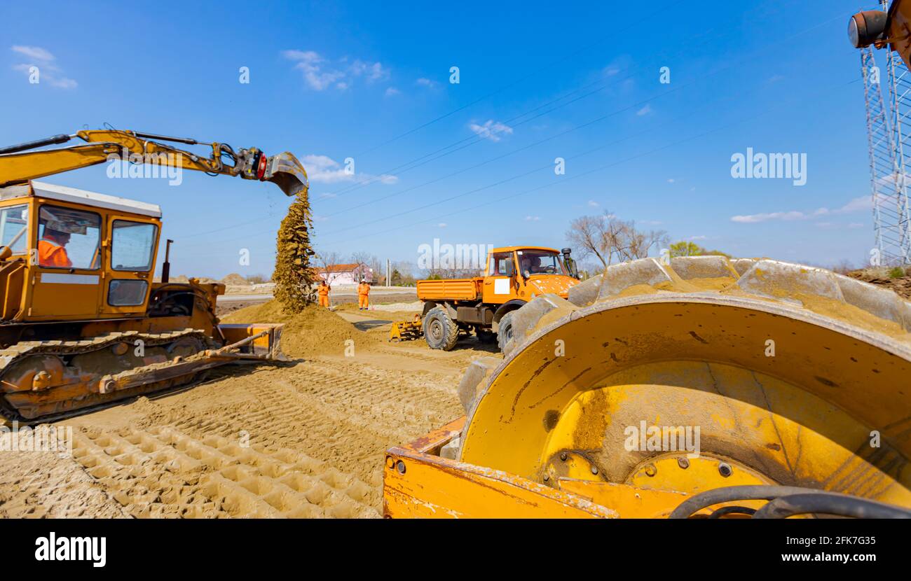 View over roller with spikes on bulldozer, excavator and truck with ...