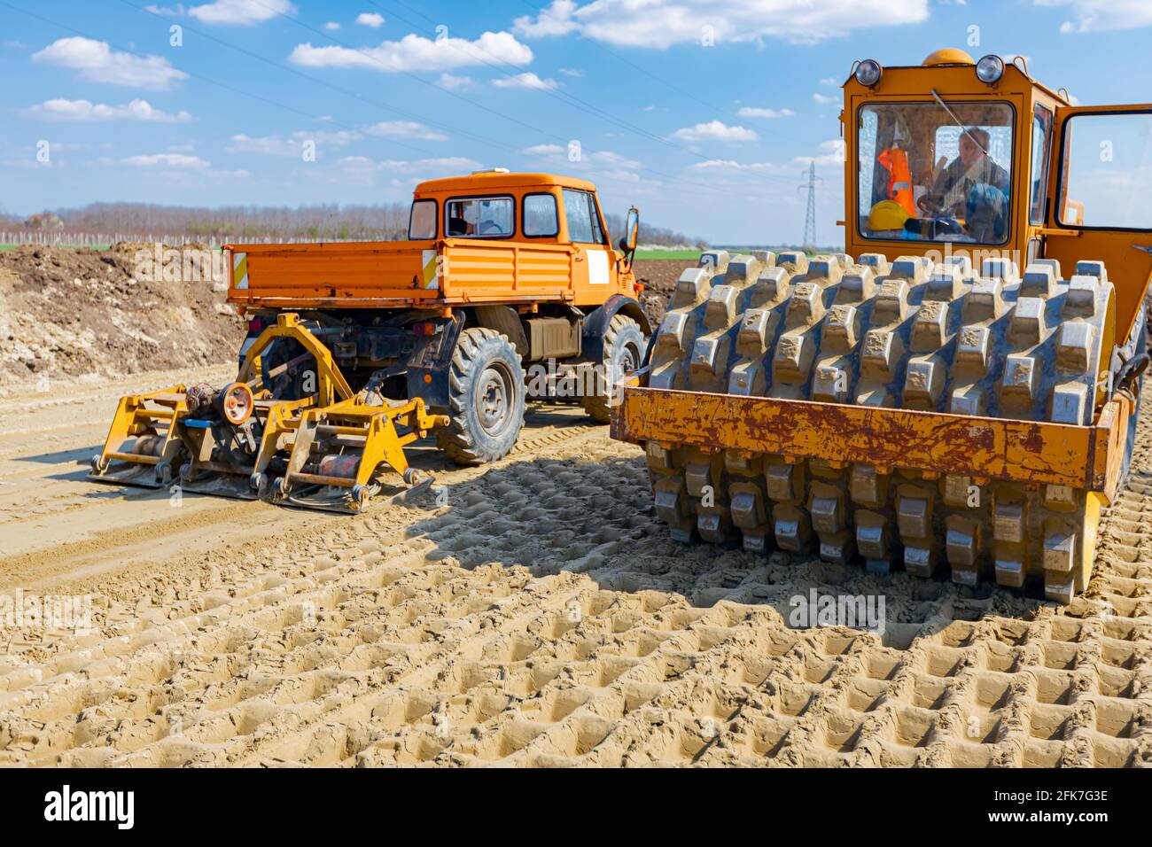 Road roller with spikes and truck with mounted plate vibration ...