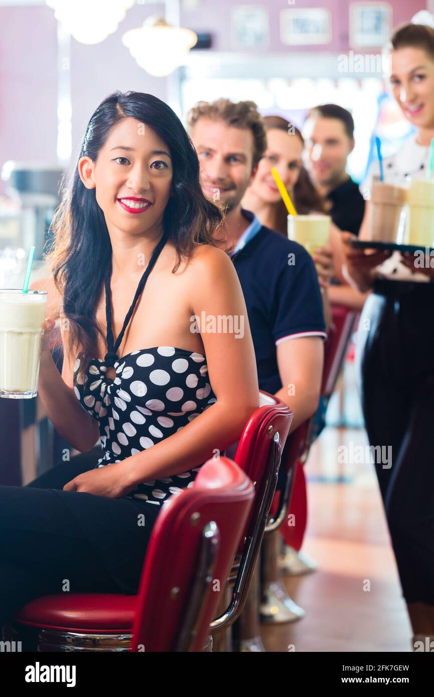 Friends or couples eating fast food and drinking milk shakes on bar in ...