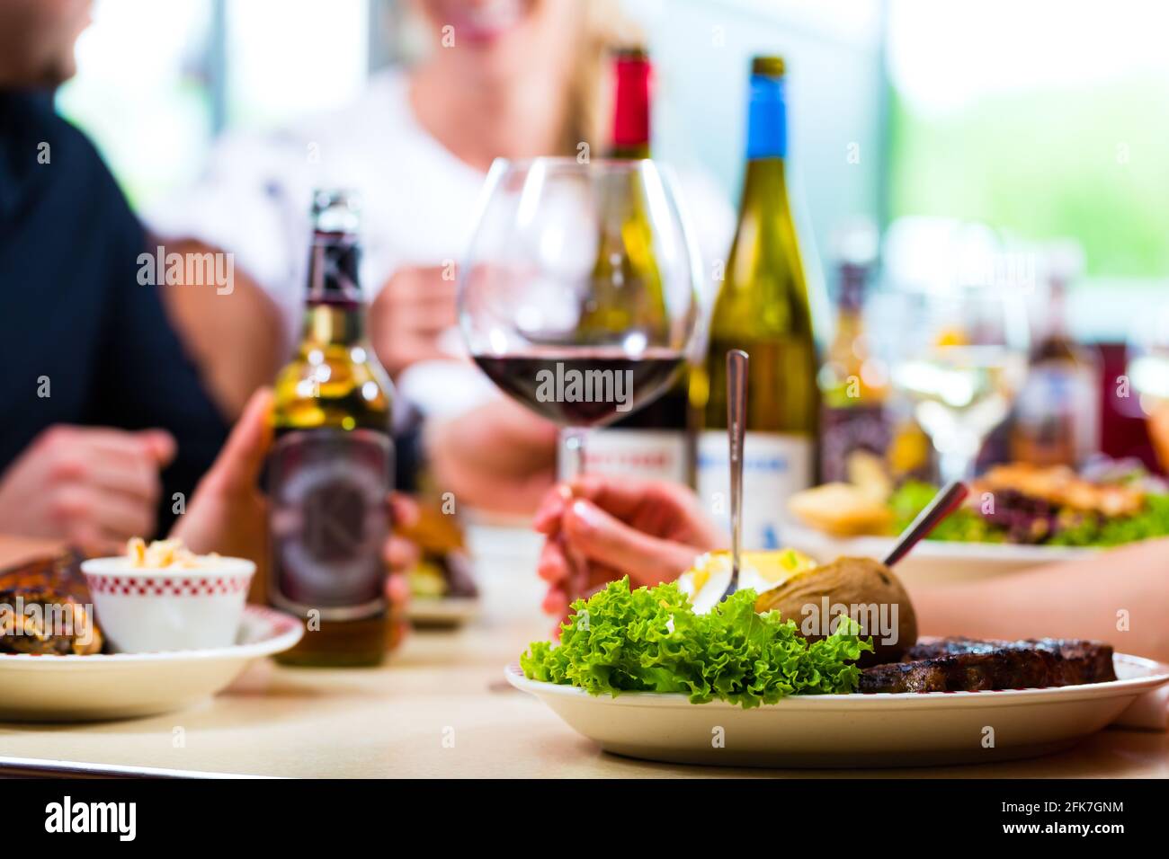 Friends or couples eating fast food and drinking beer and wine in a ...