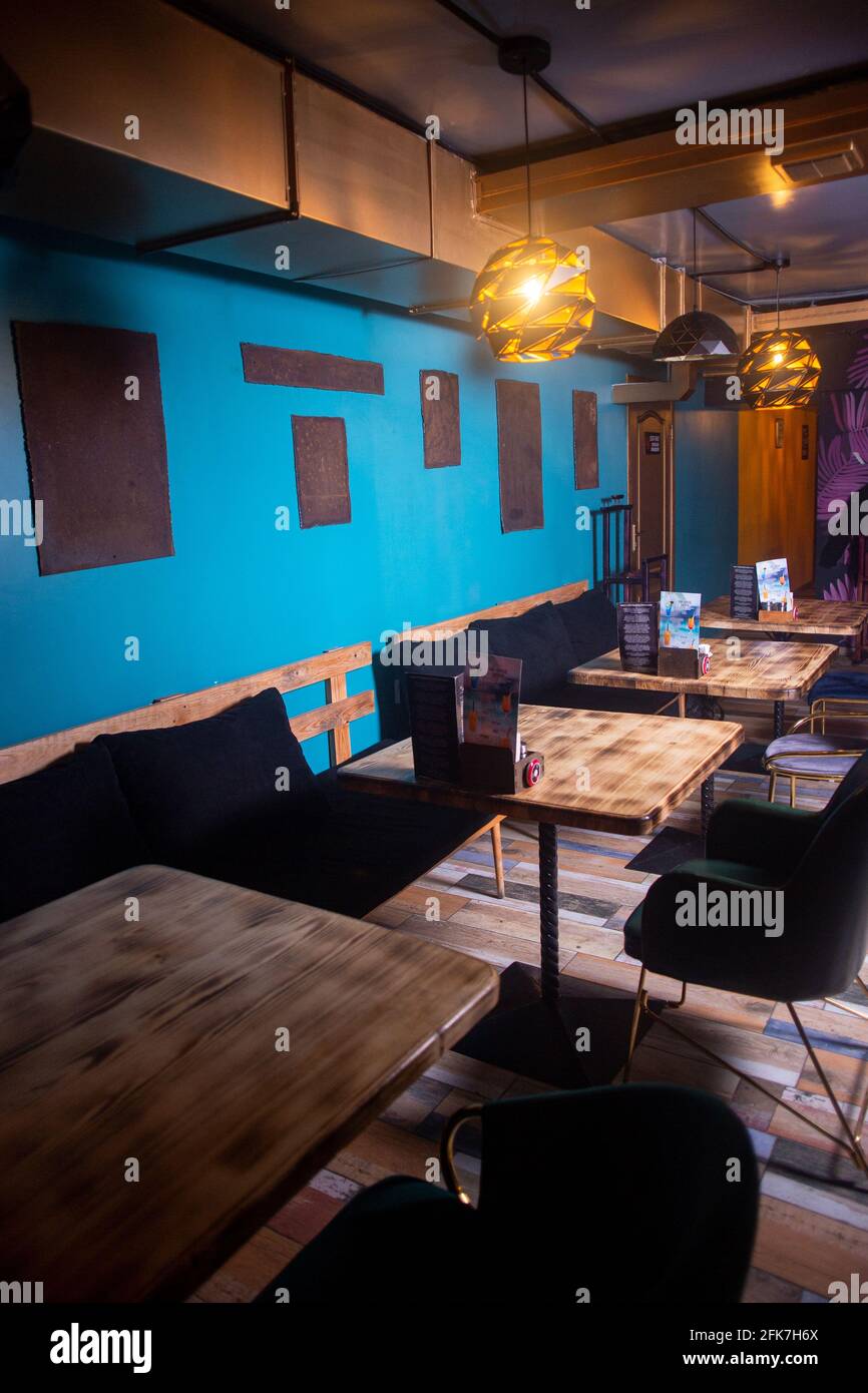 cafe interior with blue walls with black paintings and wooden tables ...
