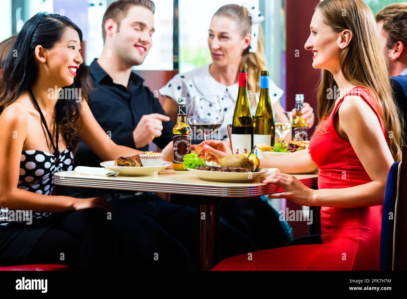 Friends or couples eating fast food and drinking beer and wine in a ...