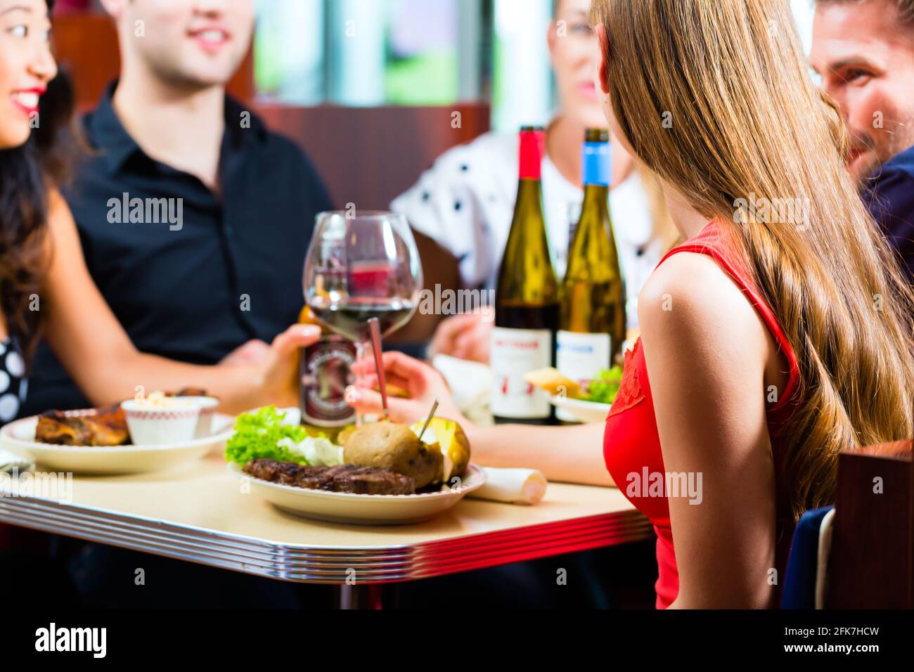 Friends or couples eating fast food and drinking beer and wine in a ...