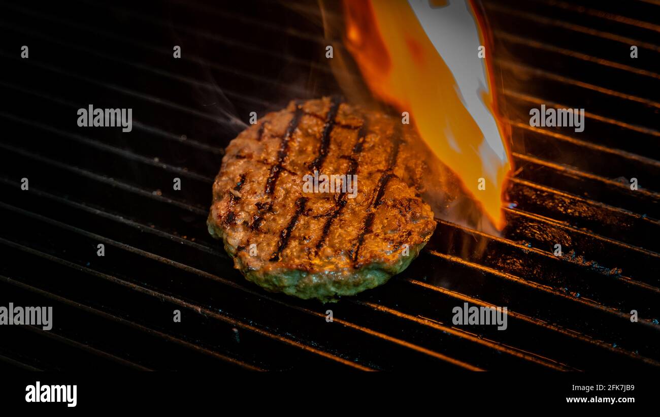 cooking burgers patty on hot grill with flames. Burger preparation ...