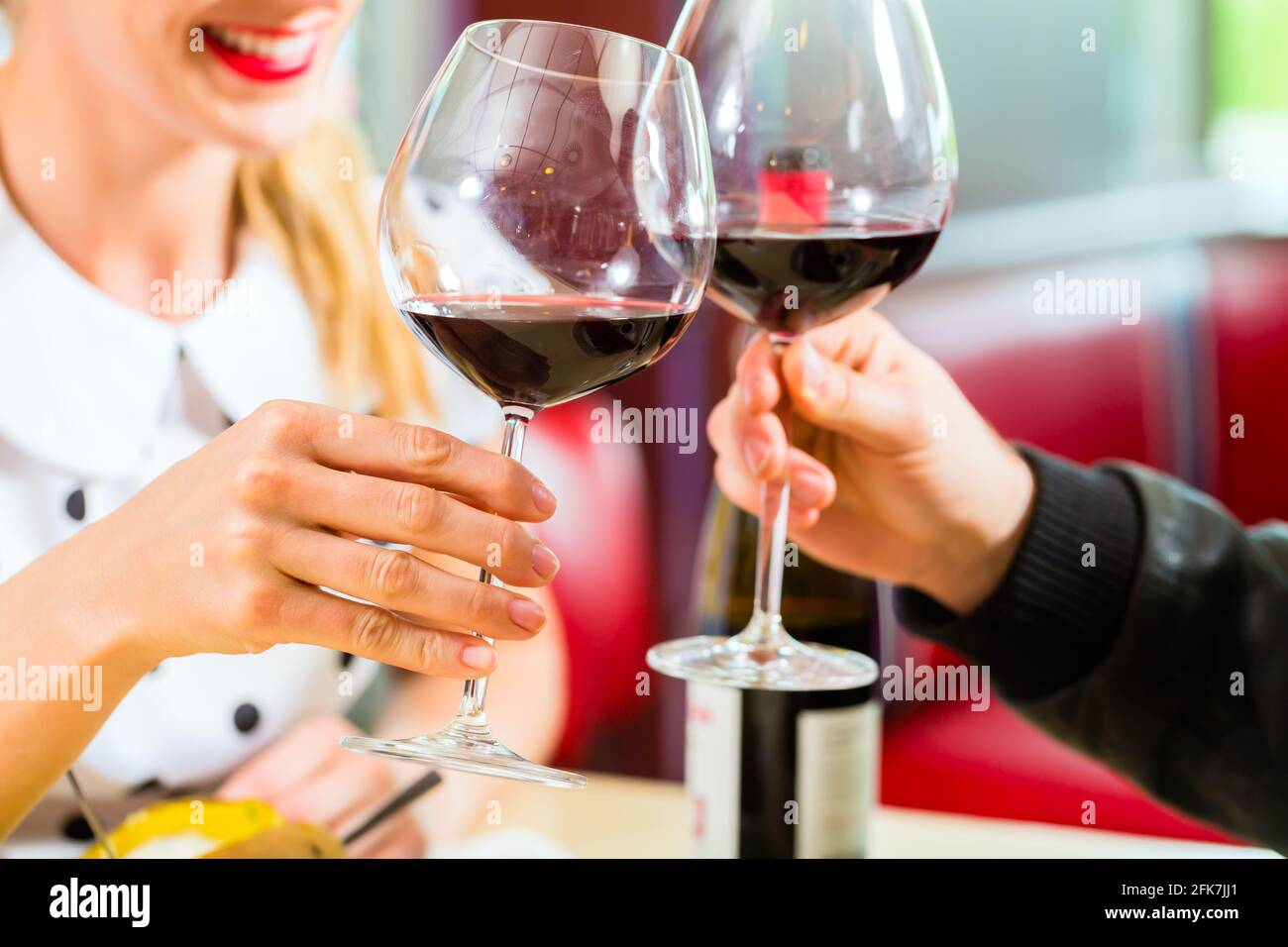 Young couple eating fast food and drinking red wine in a American retro ...