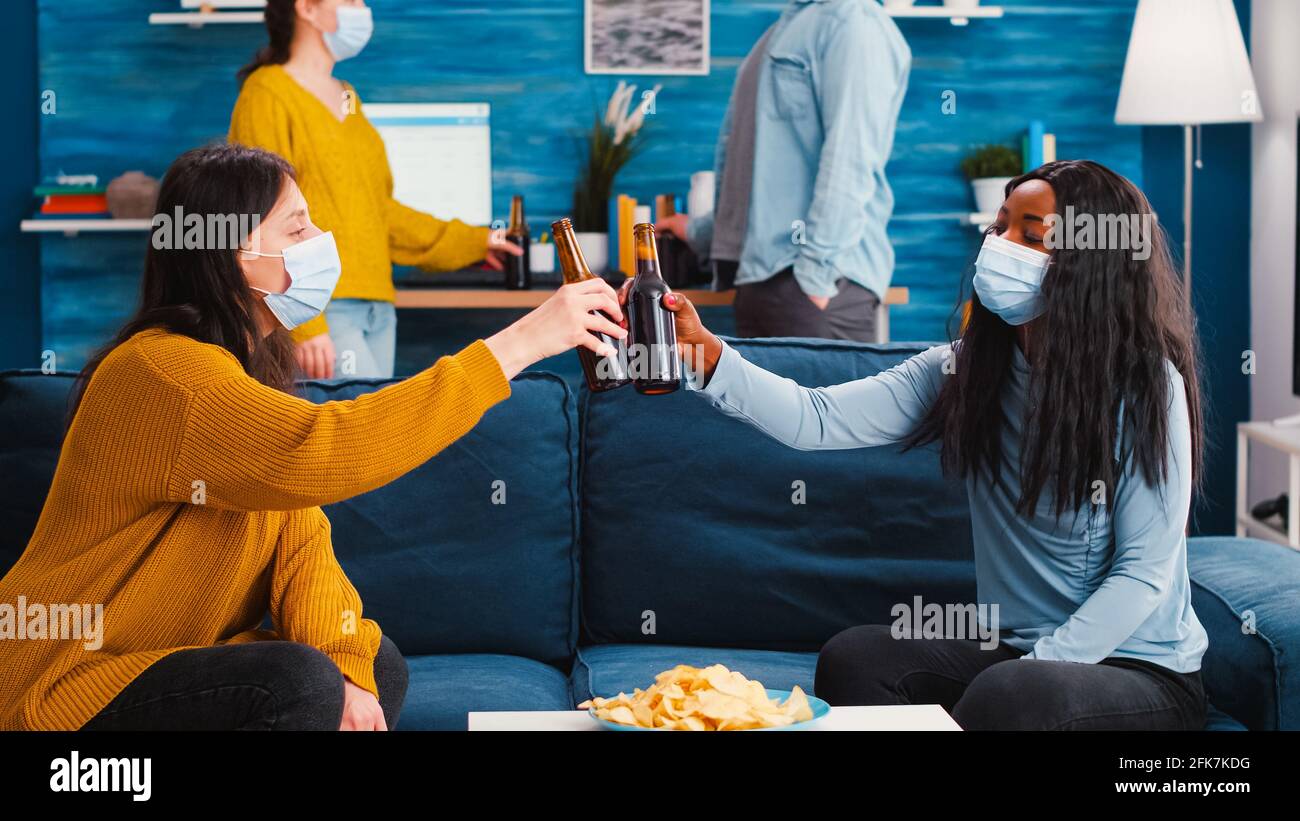 Multiracial friends with masks enjoying a beer clincking at new normal ...