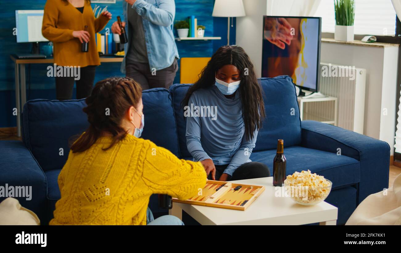 African woman competing with friends playing backgammon wearing face ...