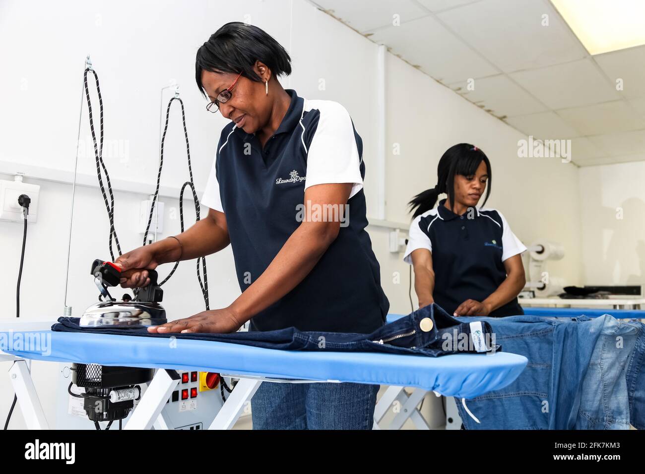 Johannesburg, South Africa - October 2, 2012: Young Black woman ironing ...