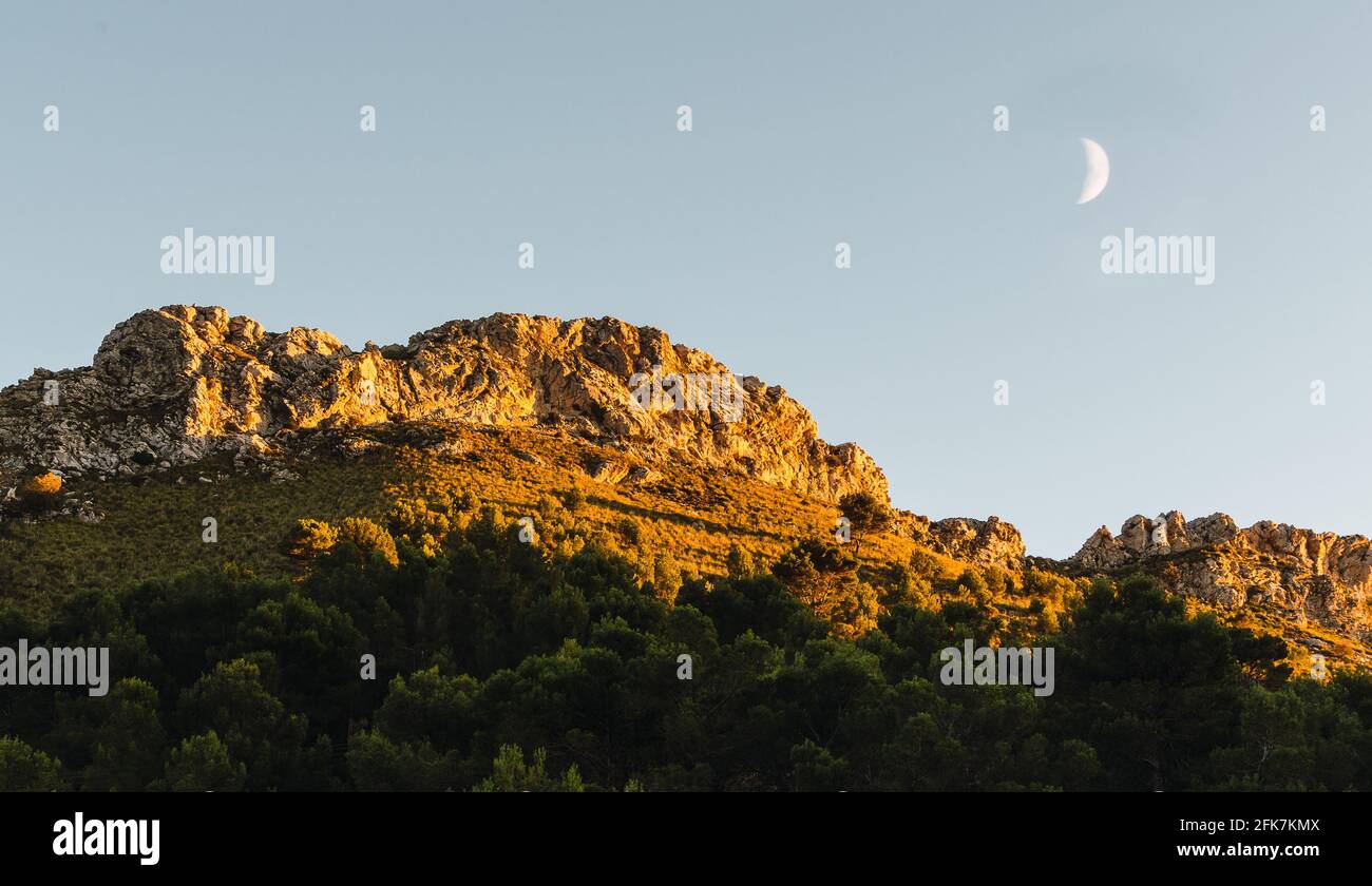 Sunset on mountain peak with waning moon Stock Photo - Alamy