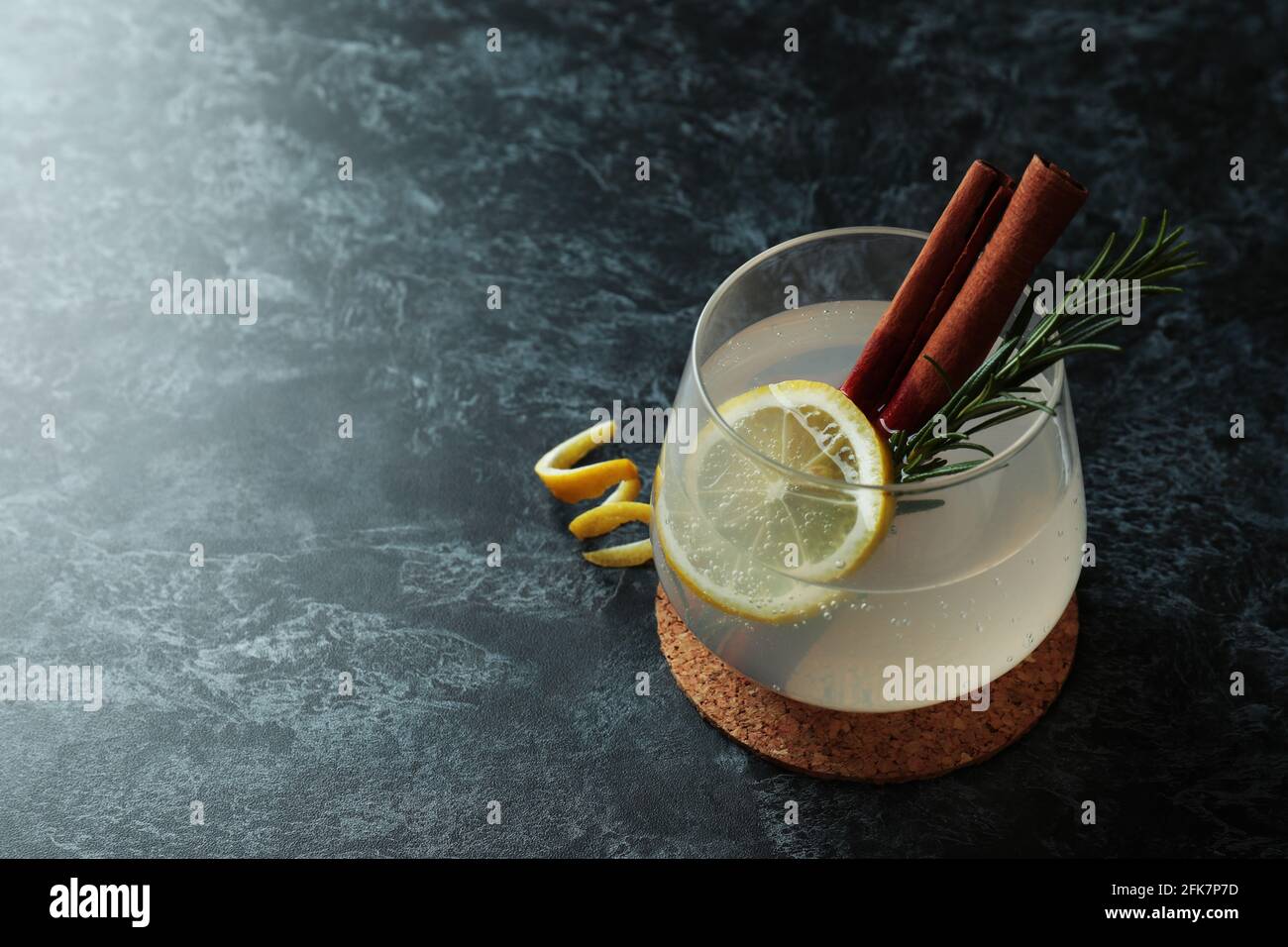 Glass of lemonade with cinnamon and rosemary on black smokey table ...