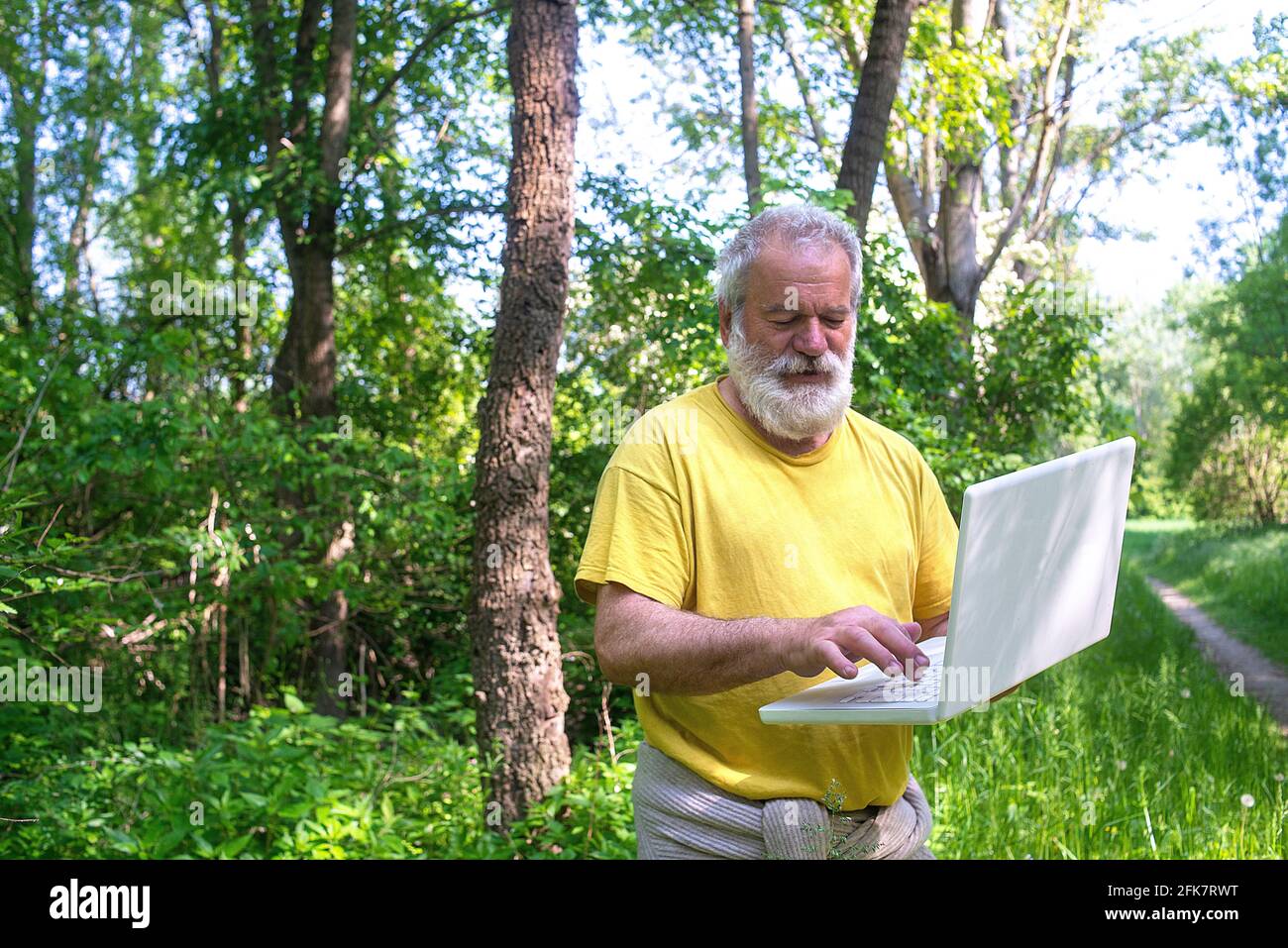 Old Spanish man with a white beard and happy face typing on his ...