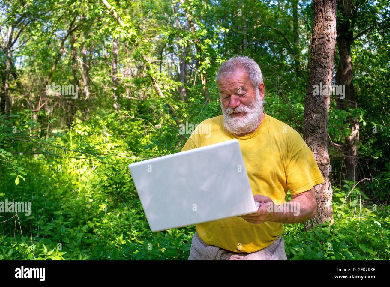 Old Spanish man with a white beard and happy face typing on his ...