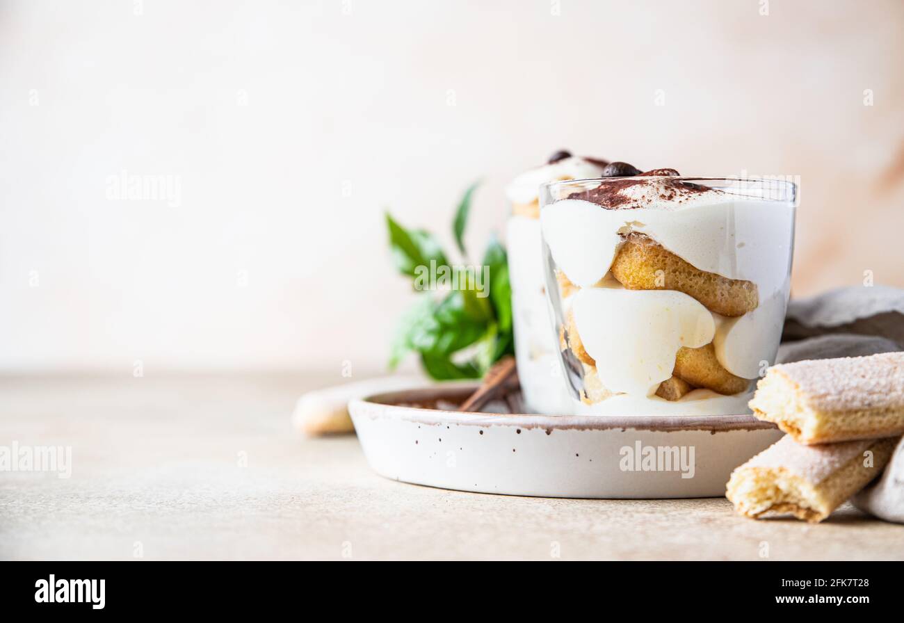 Traditional Italian dessert tiramisu in glass, light stone background ...