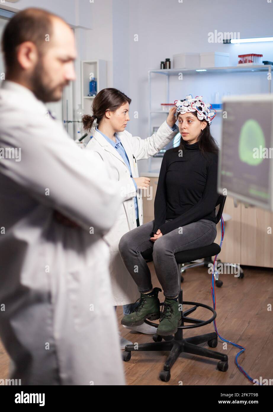 Neuroscience scientist adjusting headset with sensors on womna patient ...