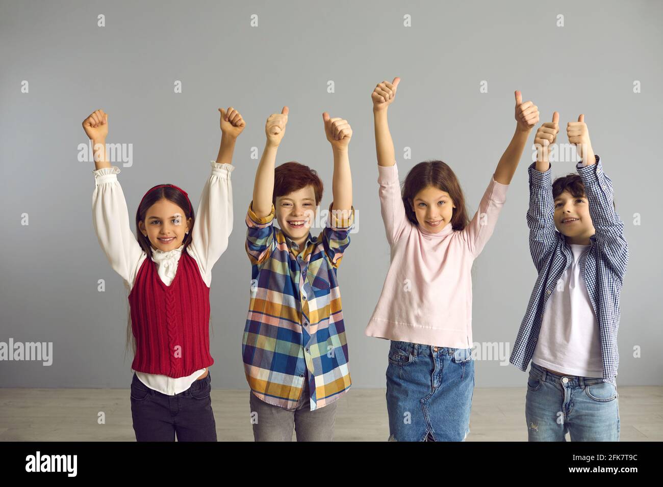 Energetic optimistic preteen children show hand up with thumbs up ...