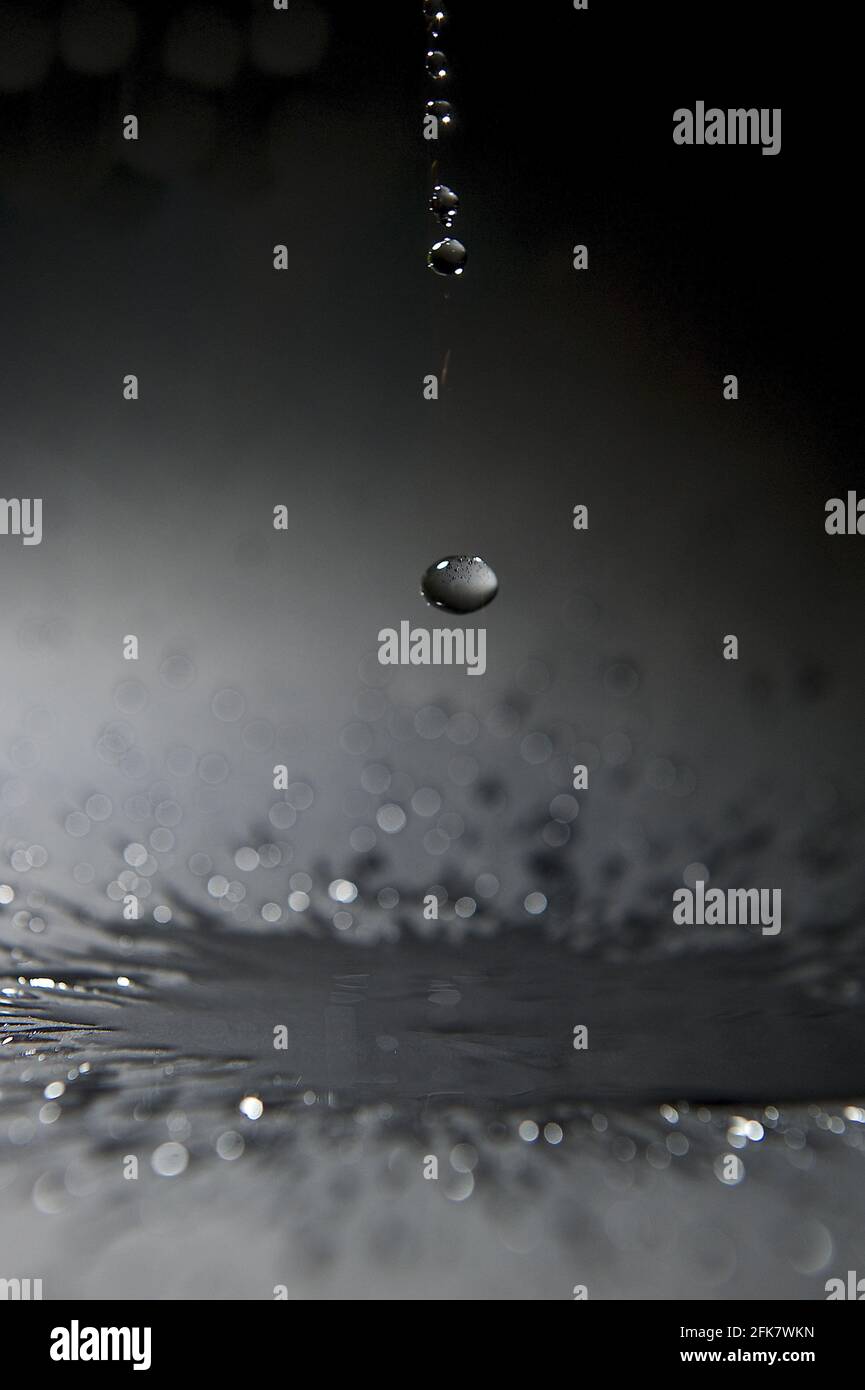 Vertical greyscale shot of drops of water dripping a surface Stock ...
