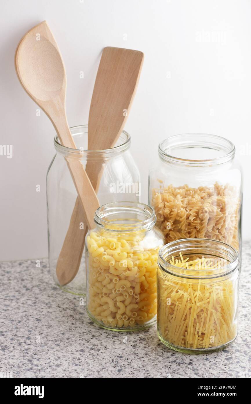 Variety of italian pasta in glass jars uncooked on white kitchen ...