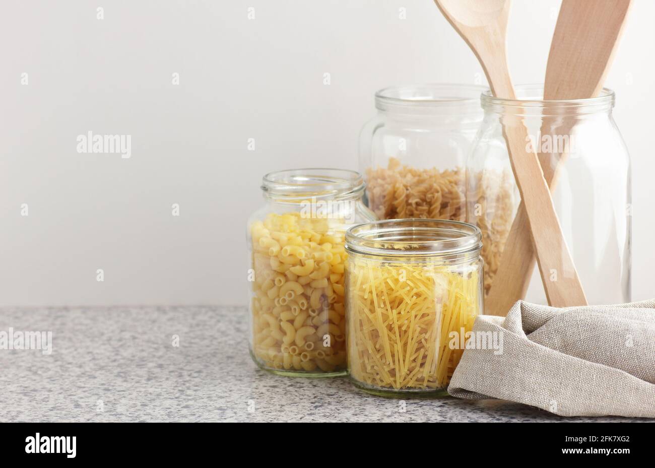 Variety of italian pasta in glass jars uncooked on white kitchen ...