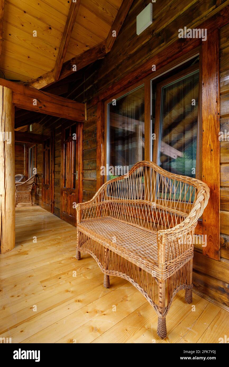 Side view of a wicker rattan bench on the outdoor terrace of a cottage ...